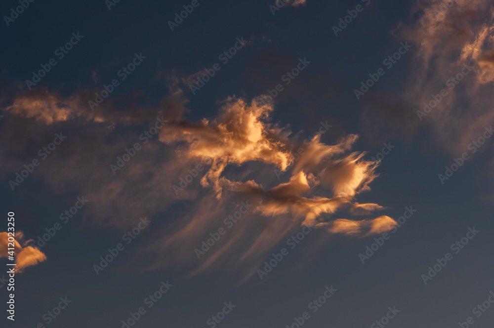 Beautiful cirrus formation in yellow and light gray colors lit by a ...