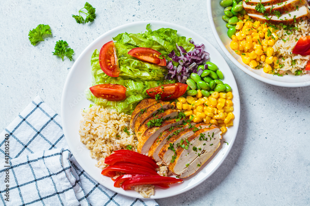 Grilled chicken breast with brown rice and vegetables in white plate ...