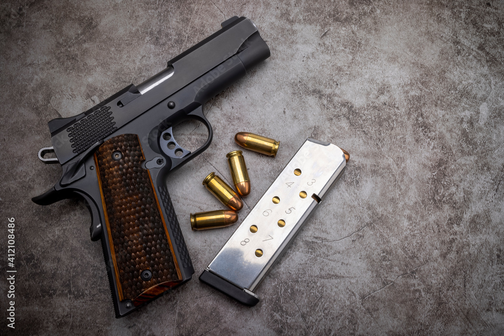 .45 Semi automatic pistol hand gun and bullets on cement texture ...