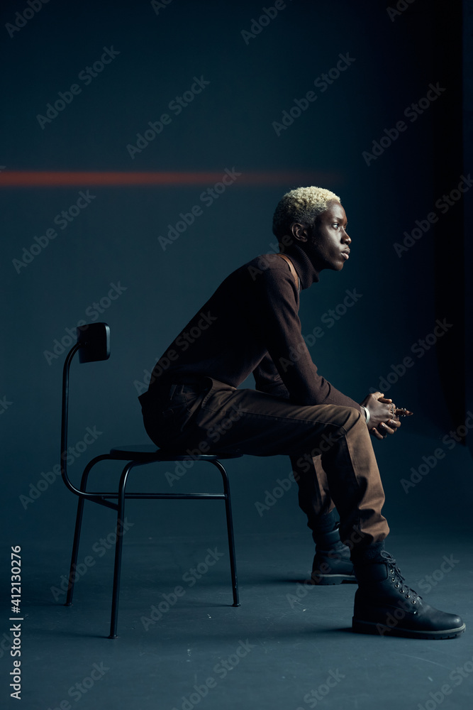 dark-skinned handsome guy with white hair and blue eyes sitting on a ...