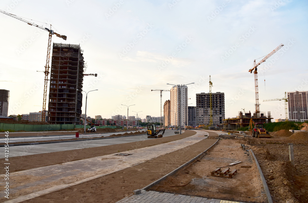 Laying paving slabs and borders at construction site. Tower cranes in ...
