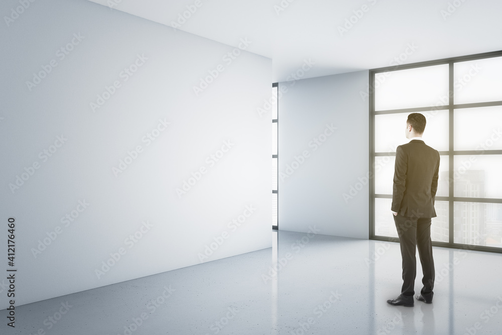 Back view on businessman staying on glossy floor in empty light room ...