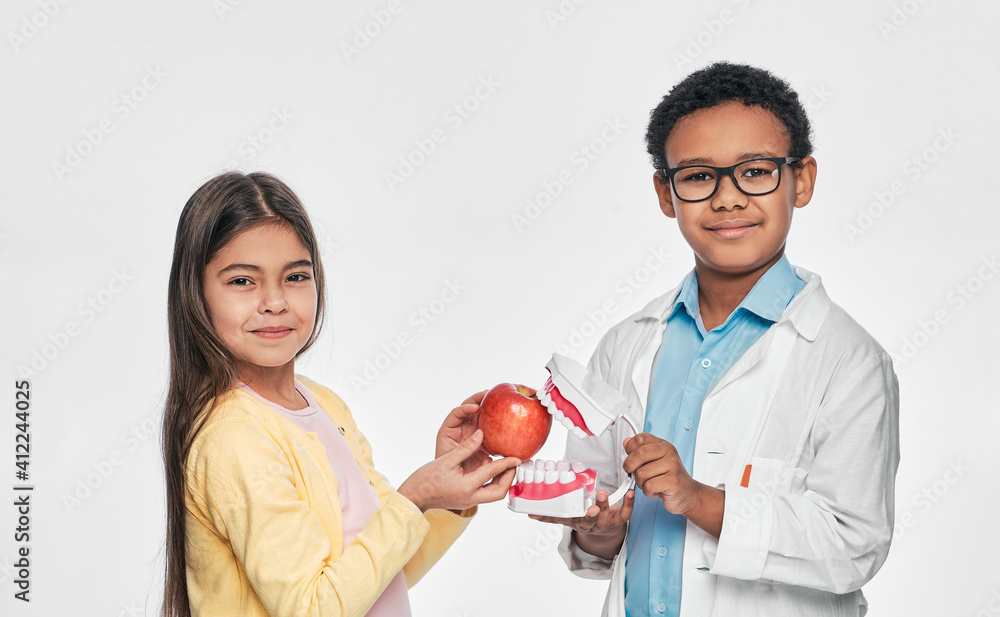 Health of child's teeth. Cute boy and girl bites an apple using human ...