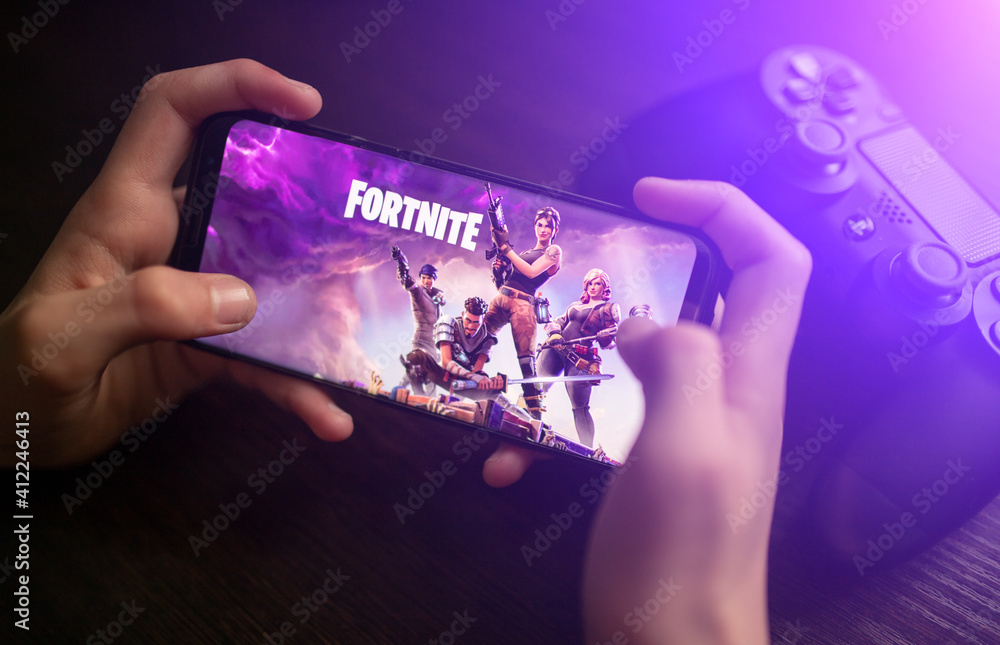 February 8, 2021: Phone in hand with the Fortnite logo on a background ...