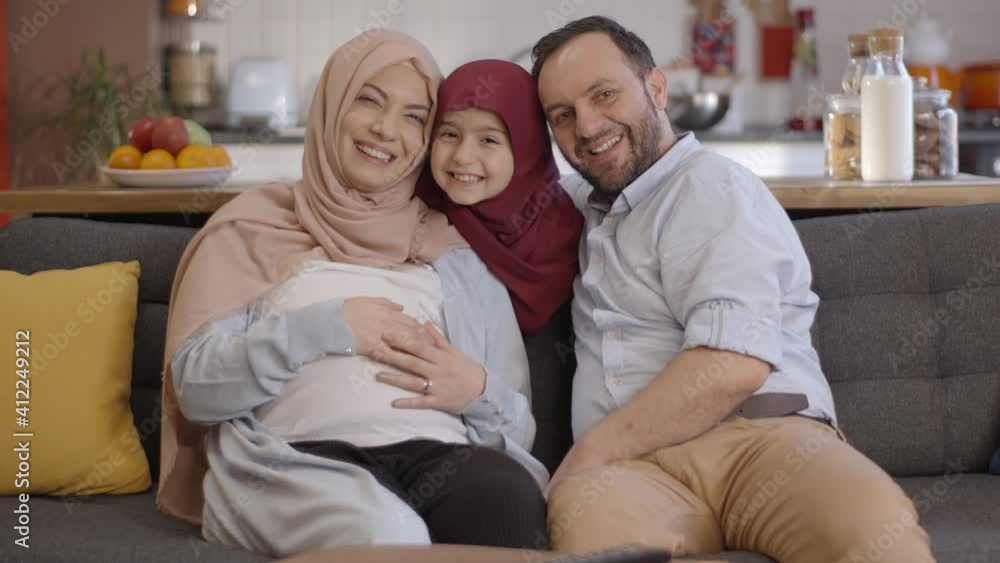 Pregnant Muslim mother wearing a hijab, her little daughter wearing a ...