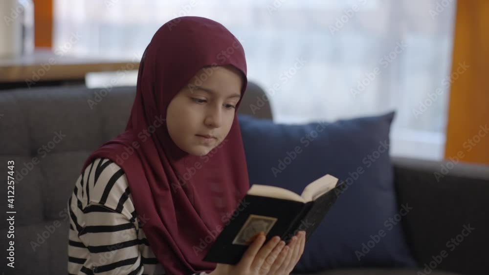 Muslim with headscarf little girl reciting the the holy Quran.The ...
