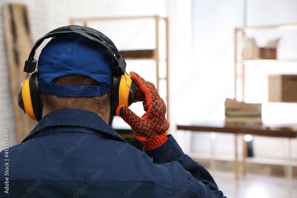 Worker wearing safety headphones indoors, back view. Hearing protection ...
