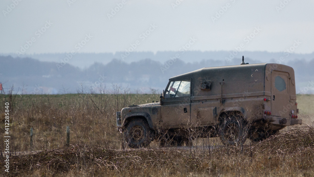 british army land rover defender 4x4 speeds along a dusty dirt track ...