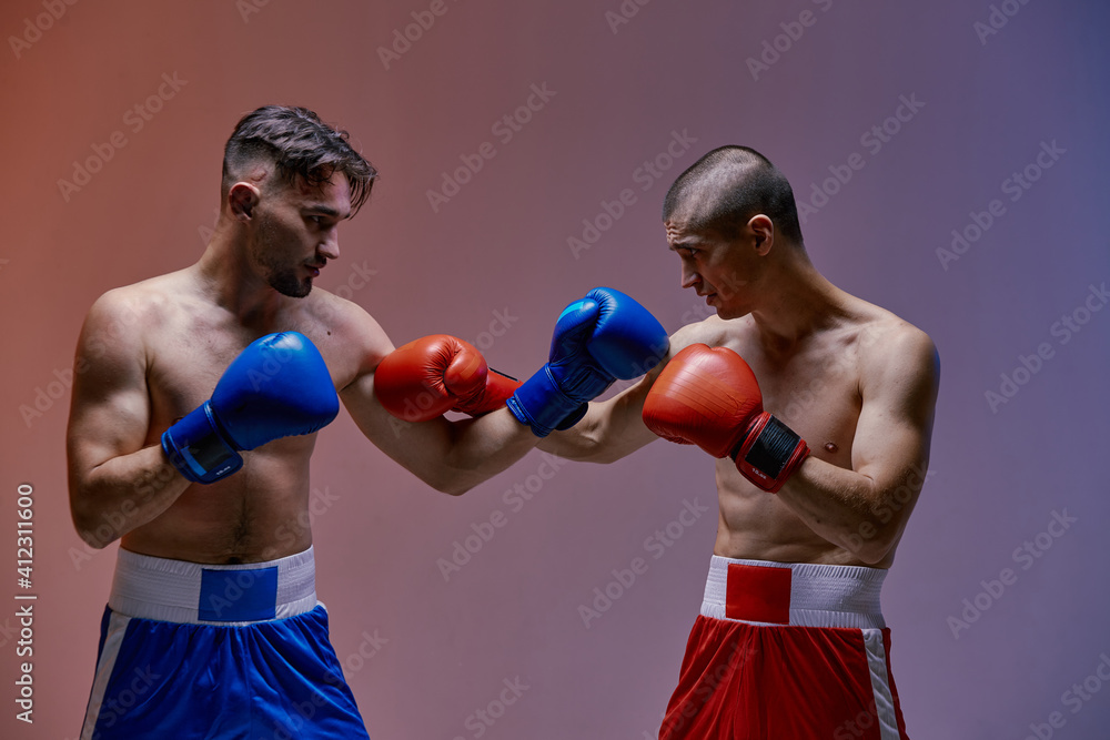 Wrestling of two fighting guys with fit torsos in boxing gloves in red ...
