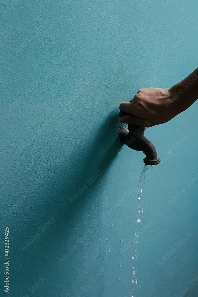 Child's hand turning off a faucet. Stock Photo | Adobe Stock