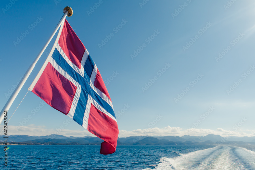 The Norwegian flag with a view from a boat of the ocean and the fjords ...