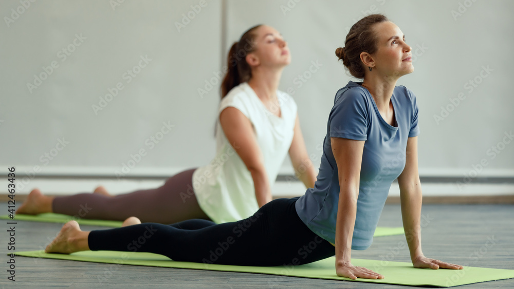 Two Caucasian good shape female Yoga players doing body stretches and ...