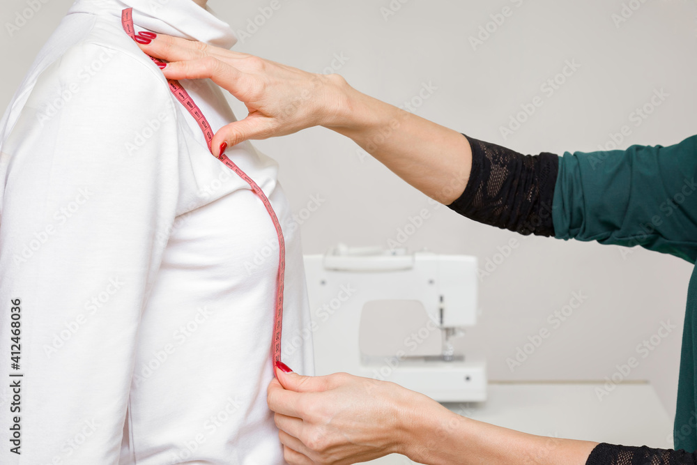 Designer hands measuring young adult woman body length with pink ...