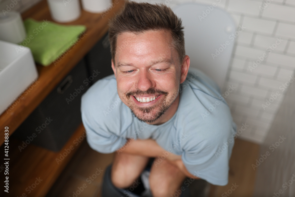 Man with satisfied smile sits on toilet. Unimpeded bowel movement ...