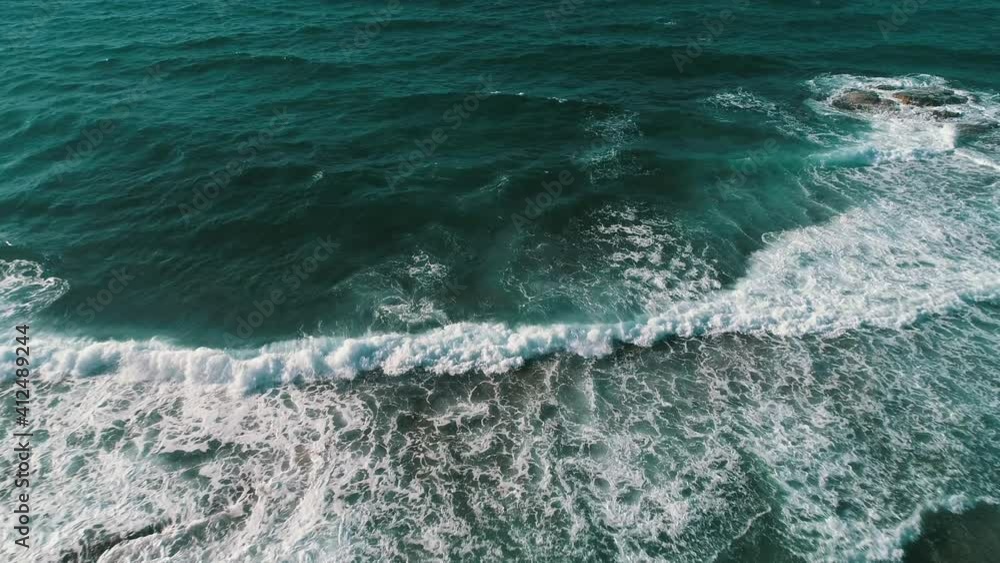 Flying over the ocean at the golden hour. Giant waves foam and splash ...