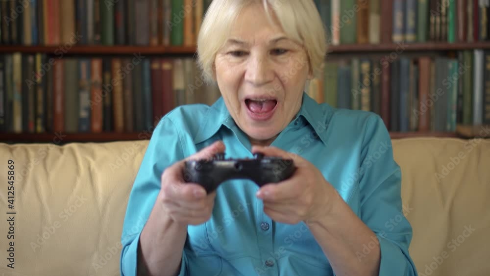 Elderly woman gamer playing video games at home during lockdown ...