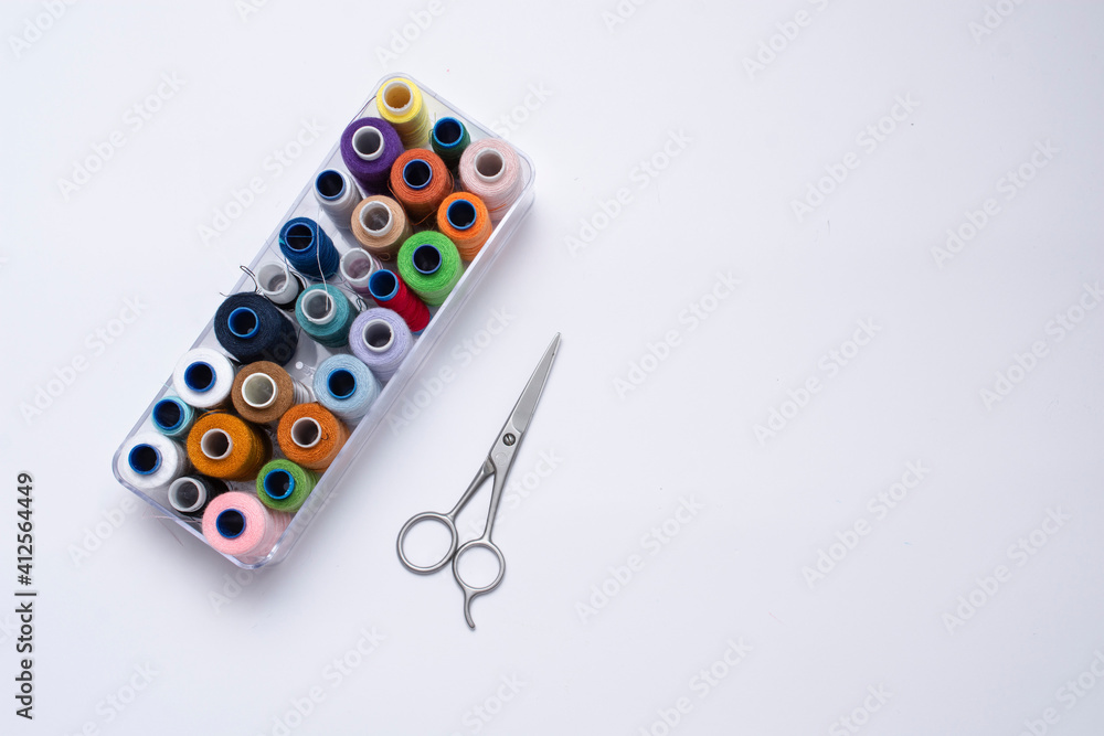 colorful different threads in transparent box and scissors on white ...