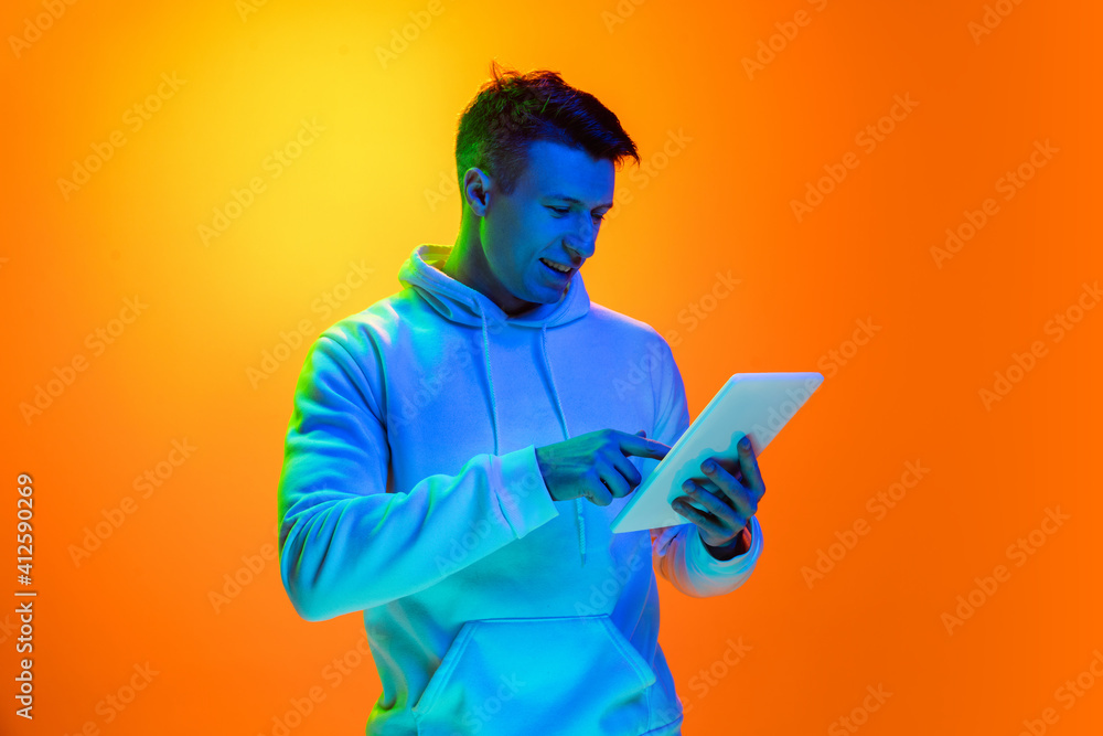 Scrolling tablet. Caucasian man's portrait isolated on yellow studio ...