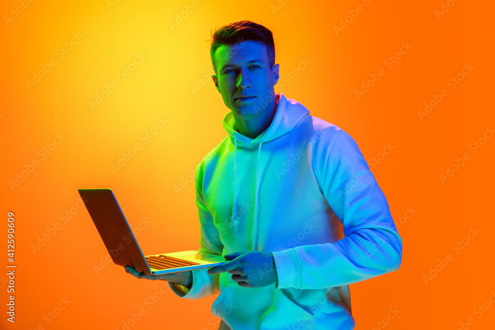 Scrolling laptop. Caucasian man's portrait isolated on yellow studio ...