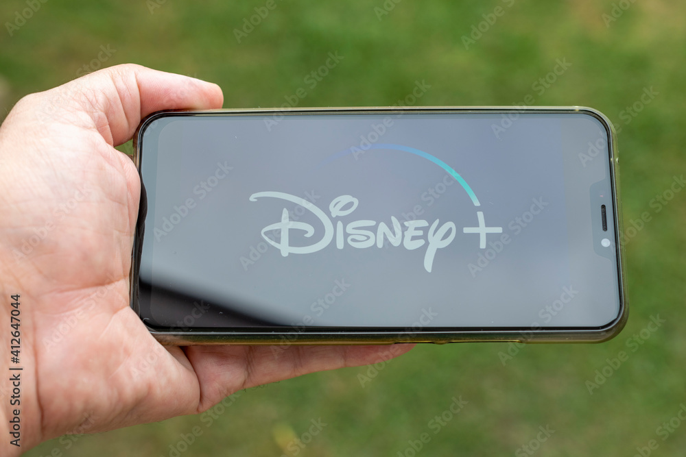 cell phone in hand with screen from the Disney + app. The streaming ...