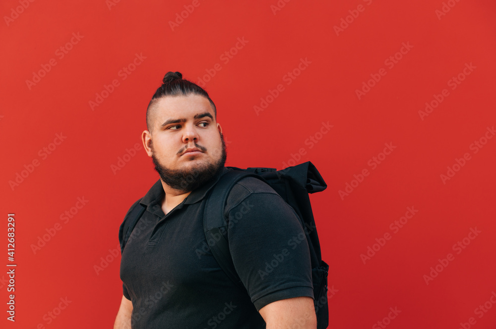 Close photo of a stylish bearded fat man in black clothes on a red ...