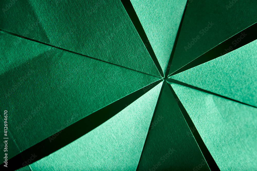 Abstract radial green background of textured paper folded using origami ...