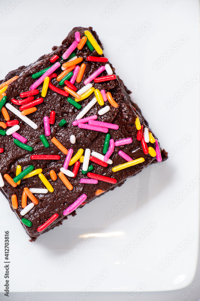 homemade chocolate frosted brownies with rainbow colored sprinkles on a ...