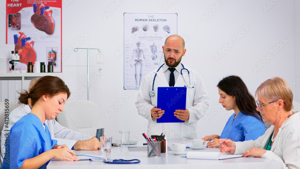 Medical staff listening to lecture, asking questions and taking notes ...