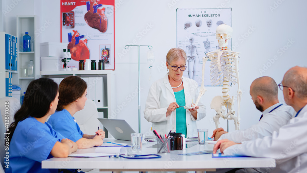 Elderly woman doctor showing the work of human's hand on skeleton ...
