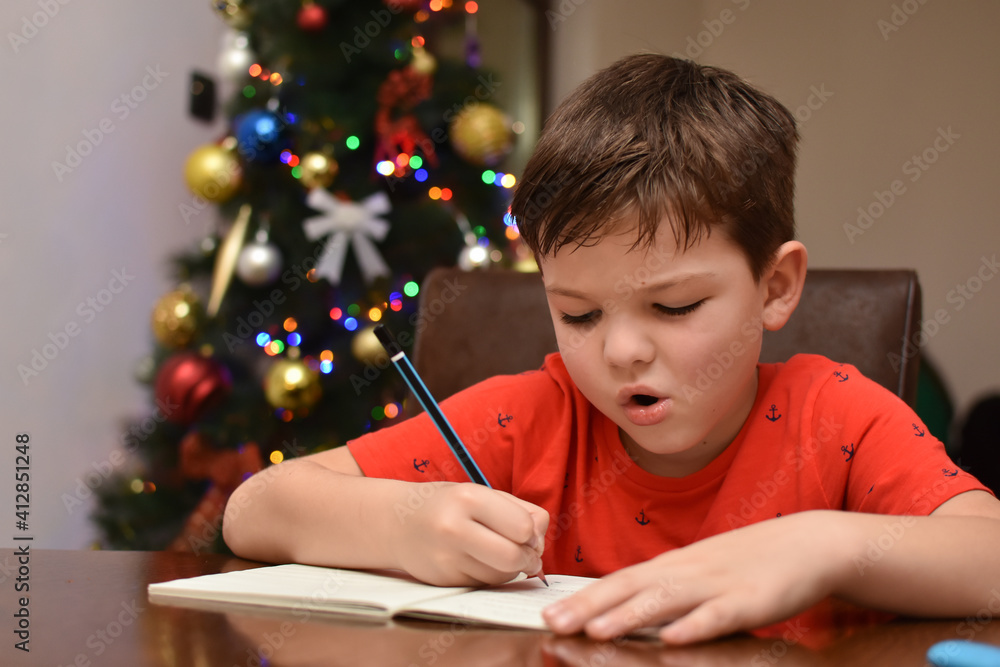 Beautiful young boy doing homework for holidays. Kid studying on table ...