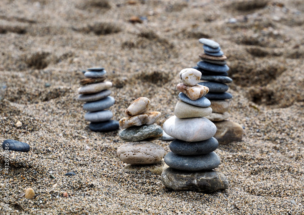 Pyramids of small stones rise above the sand. Flat and oval pebbles are ...
