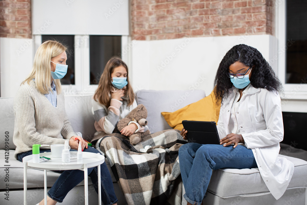 Doctor visiting patient at home during pandemy. Attractive African ...