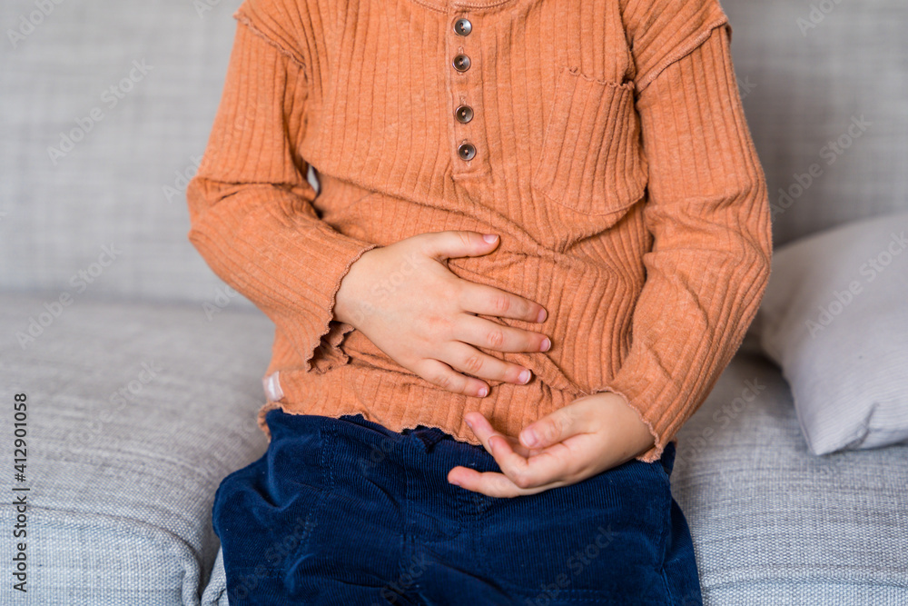 Little child putting hands on belly and suffering from stomach pain ...