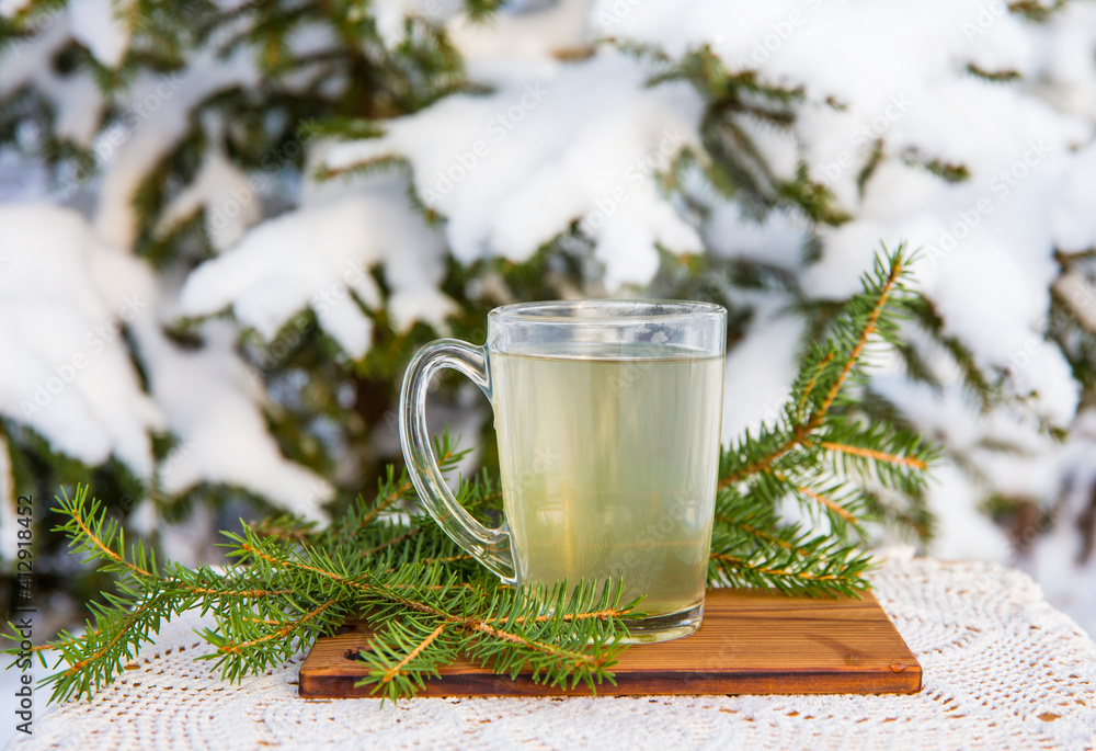 Spruce tree needle tea infusion in transparent glass tea cup. Snowy ...