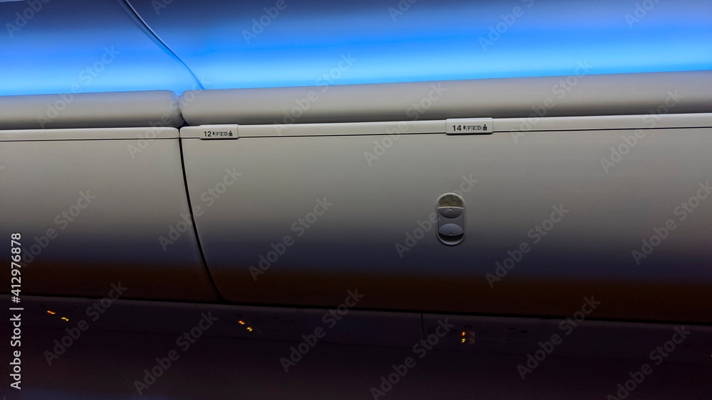 Overhead cabin luggage compartment in an modern airplane. The 13th seat ...