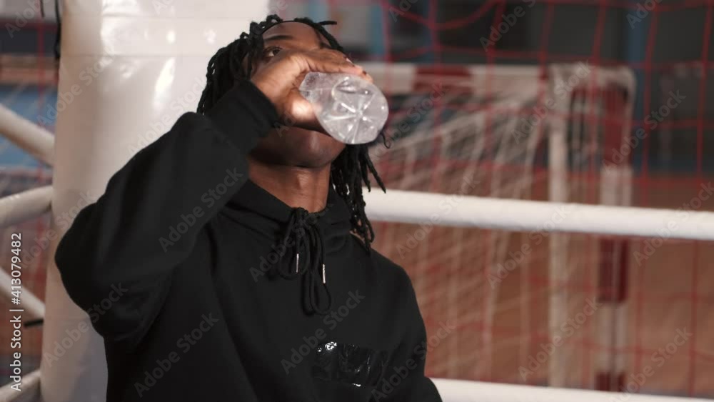 African American male young boxer sitting on chair in corner of ring ...