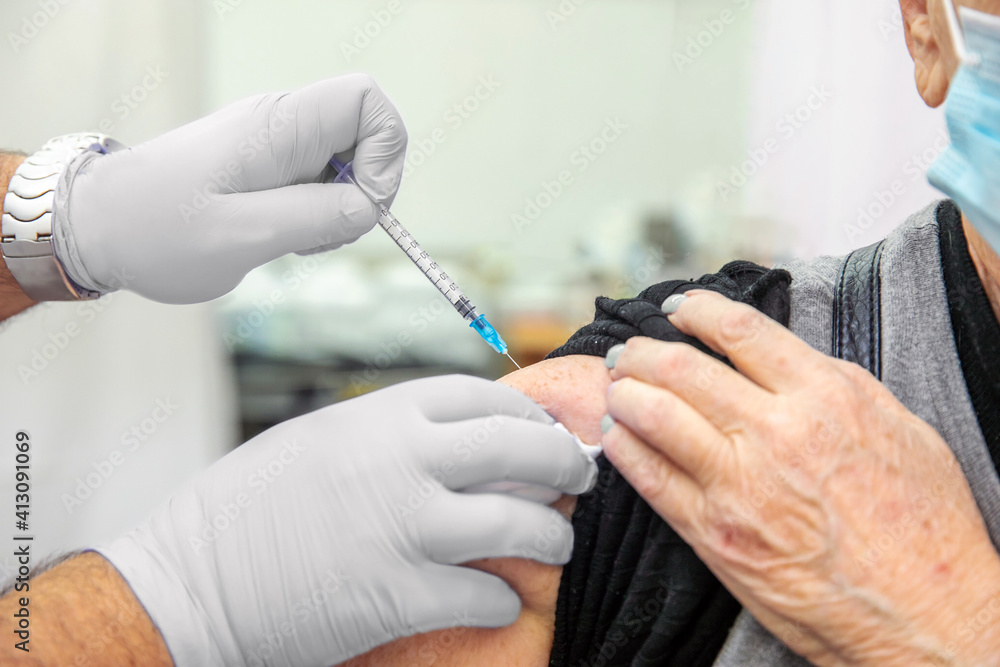 Doctor vaccinating old patient in clinic with monouse syringe. Health ...