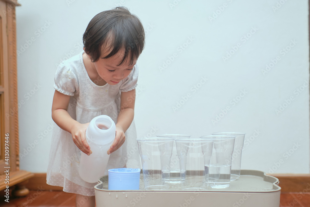 Cute Asian toddler girl having fun playing with water table at home ...