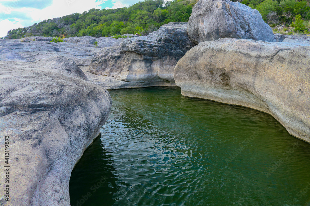 Geological rocks and pools of water flow between the limestone ...