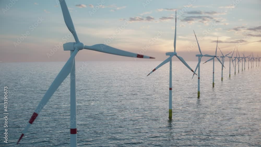 Camera pulls back to show an aerial view of a long row of offshore wind ...