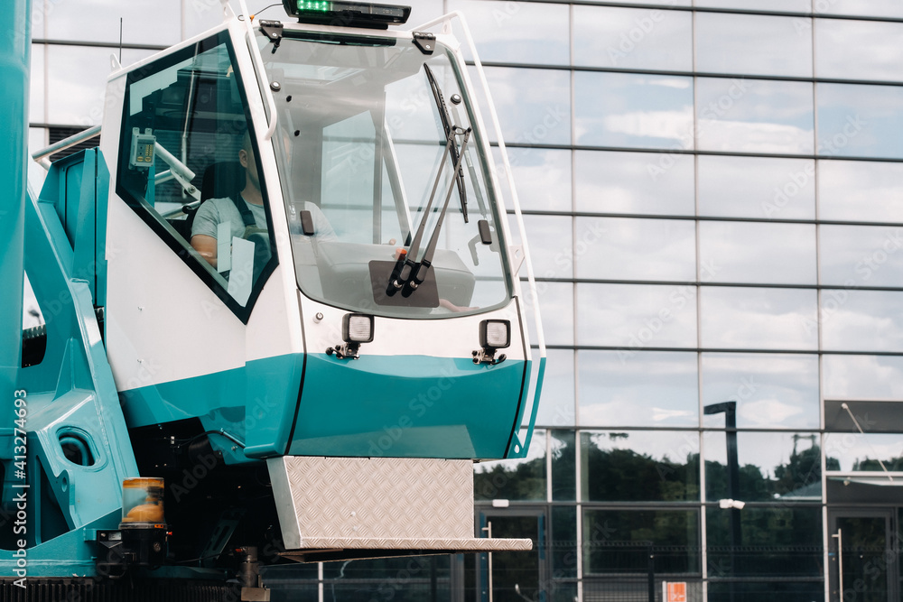 a cab with the operator of a Large blue car crane that stands ready to ...