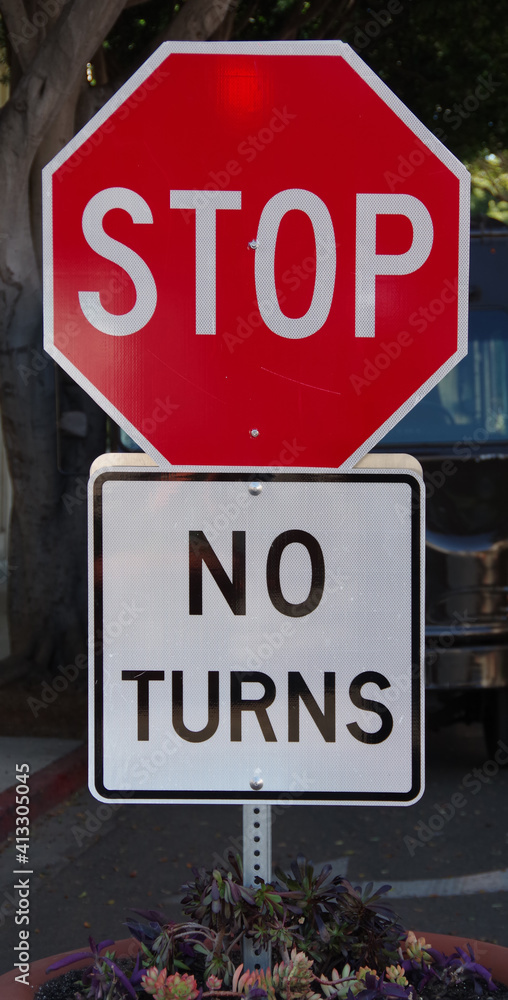 A temporary STP and NO TURNS traffic signs in a large planter pot ...