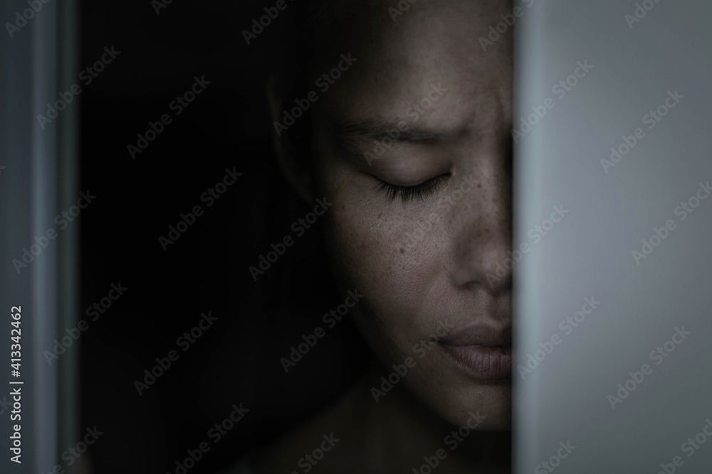 A sad afraid woman hiding in a dark closet alone at home. Stock Photo ...