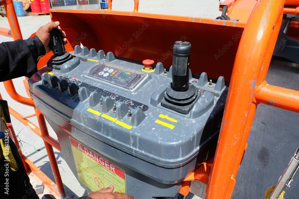 Workers are use control panel to driving the Orange articulate boom ...