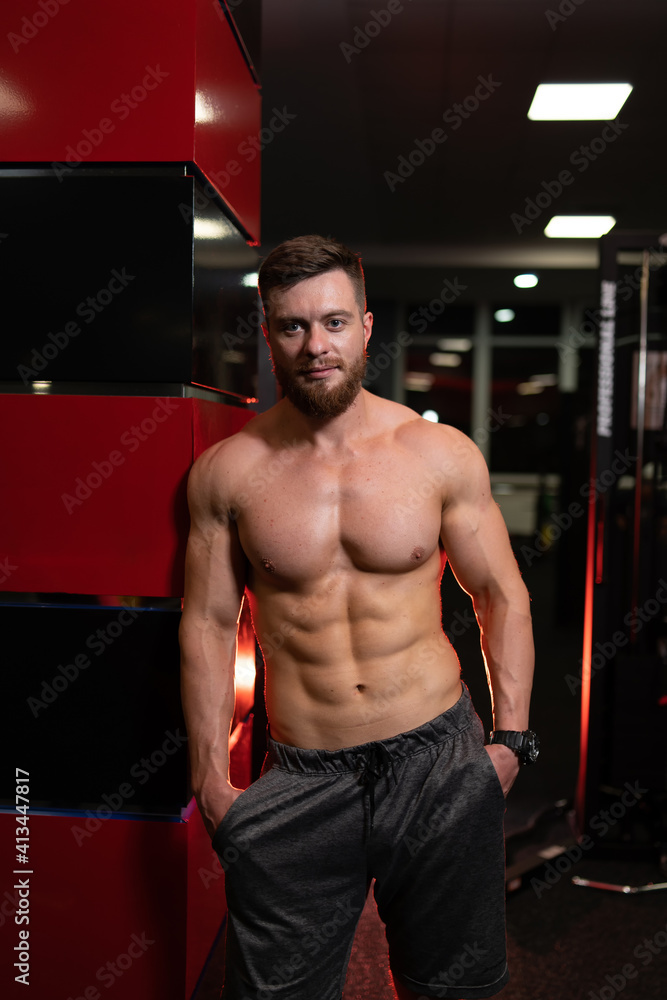 Sportman stands with hands in pockets leaning to the column at gym ...