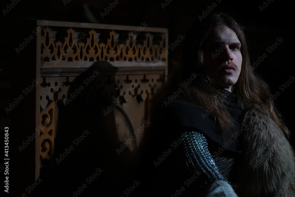 A mighty hero with long hair in chain mail armor in an ancient hall ...