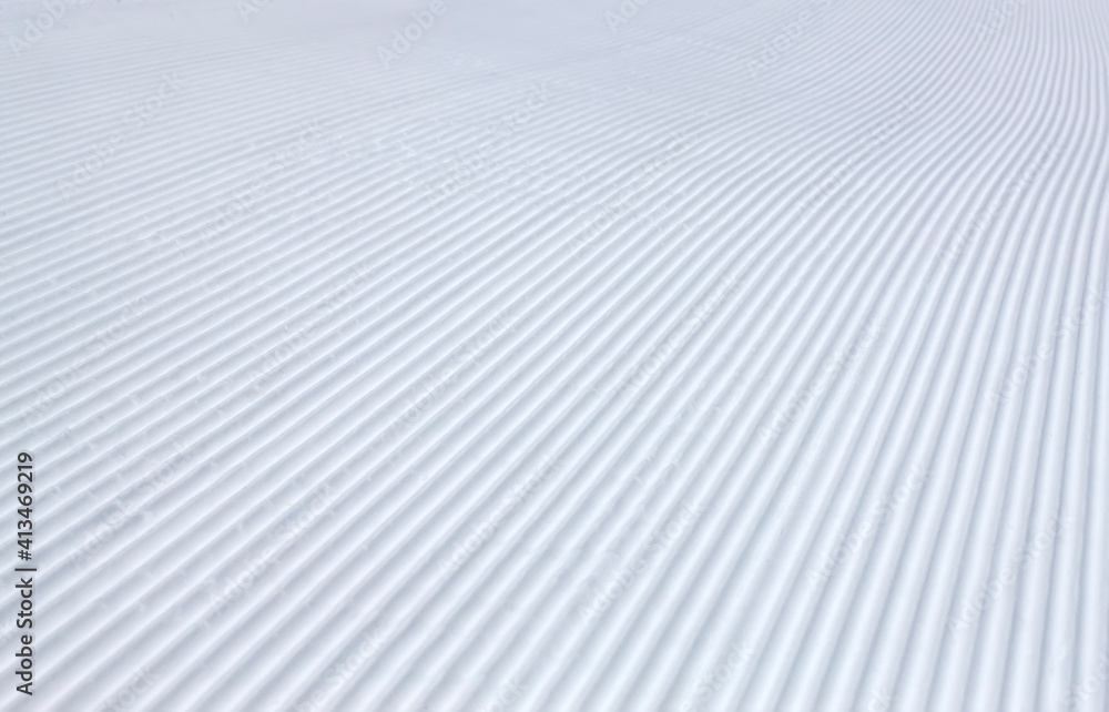 rolled and groomed ski slope, rilled snow background texture in winter ...