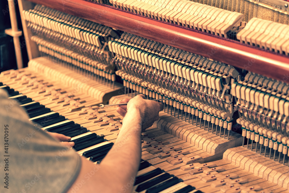Piano tuning process. closeup of hand and tools of tuner working on ...