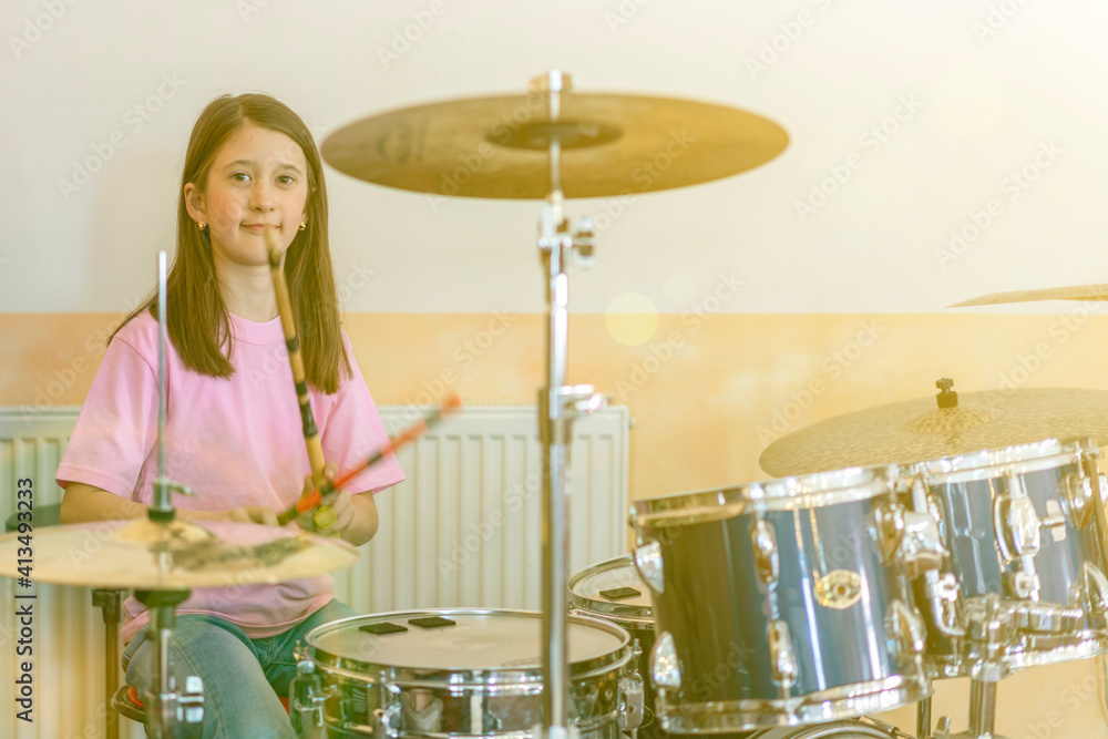 Happy girl in music therapy by playing drum kit on music room ...