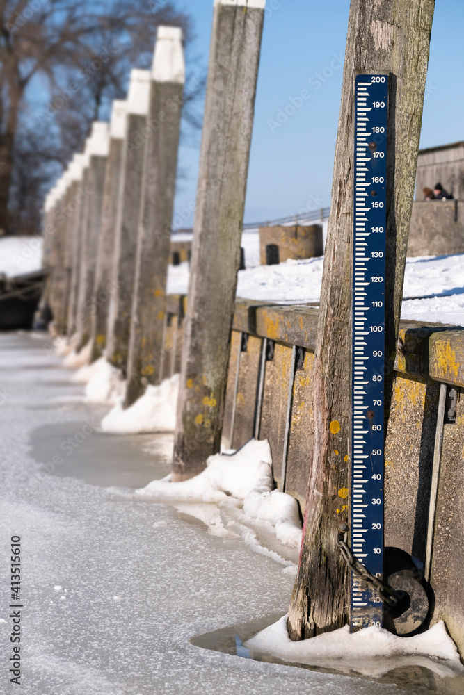 Gauge attached to a bollard in a frozen lake in the Netherlands, which ...